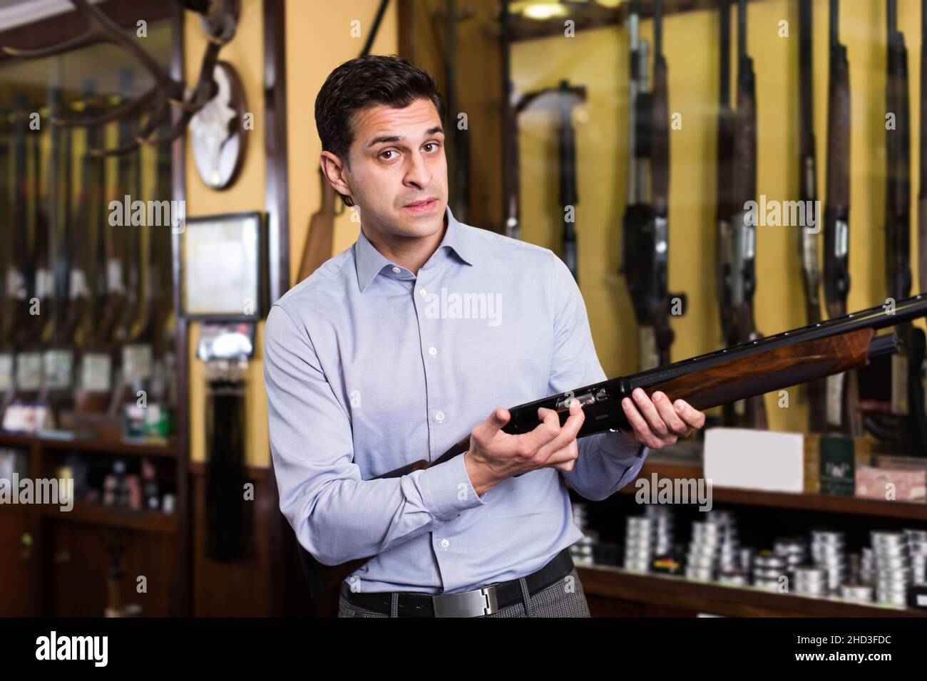 Adult male seller in hunting shop demonstrating shotgun Stock Photo - Alamy