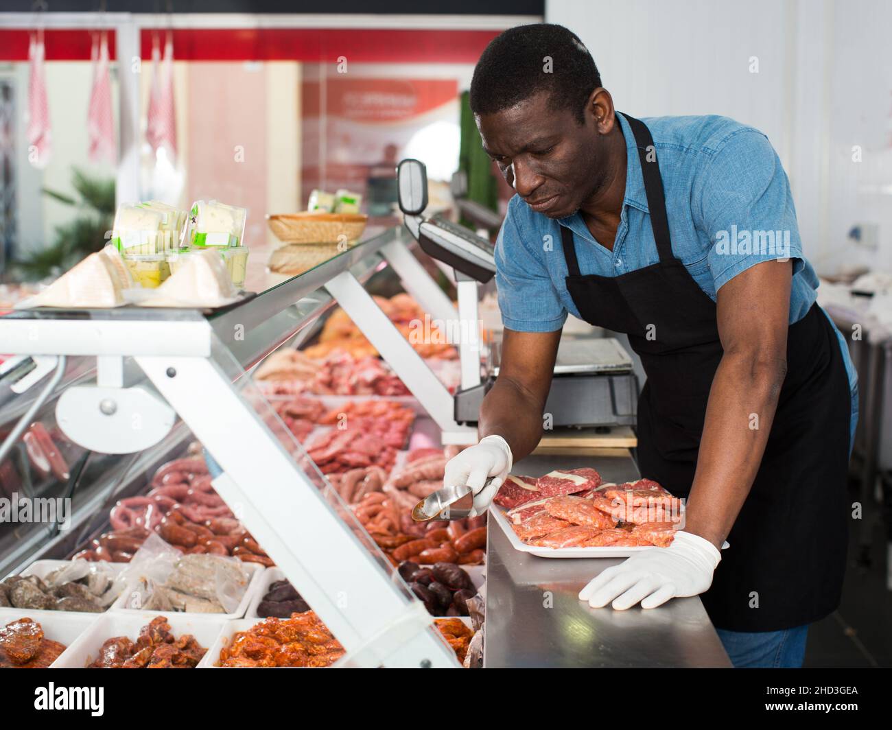 Butcher working behind counter Stock Photo - Alamy