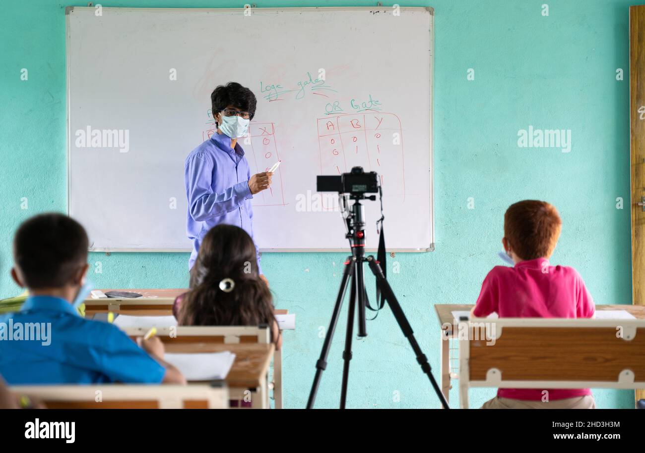 Teacher in medical mask with limited kids teaching and streaming live ...