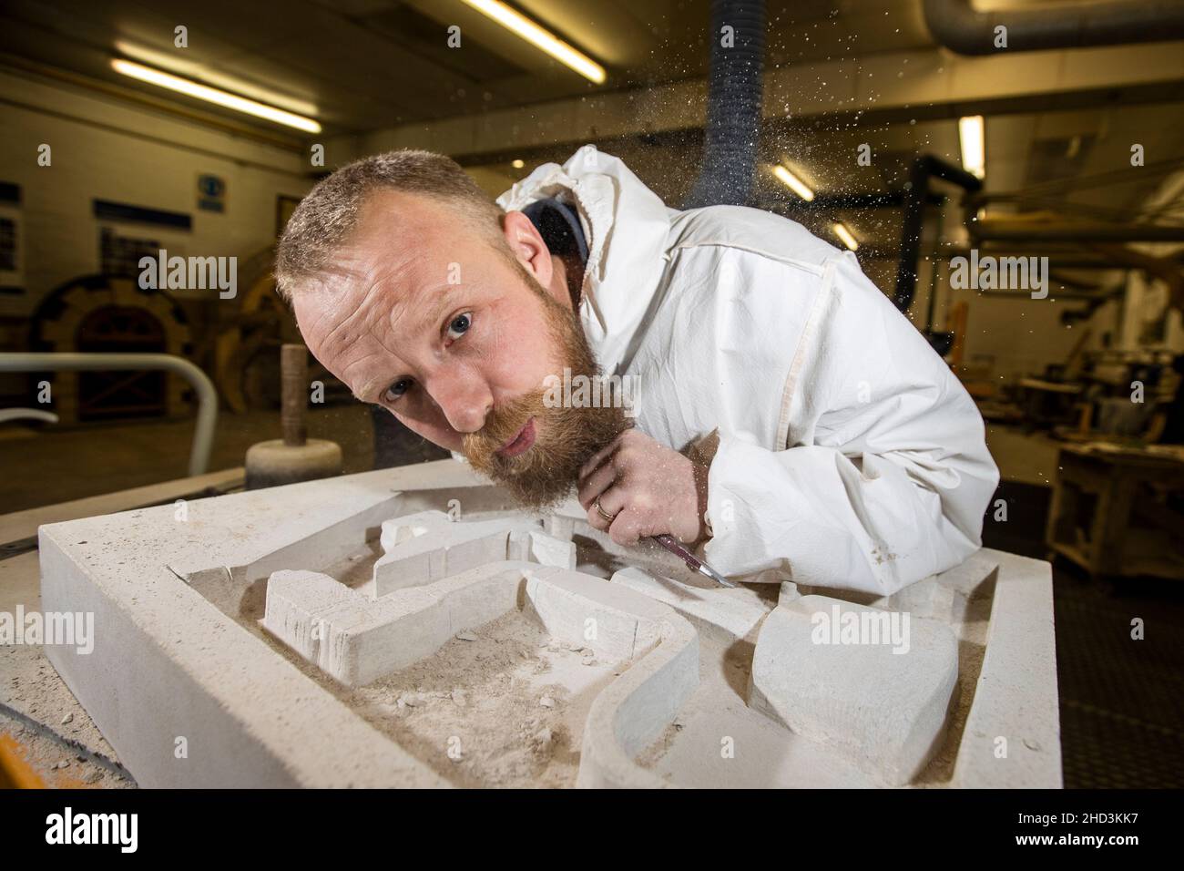 Banker Mason Stephen Hamilton blowing dust from a stone he is carving ...