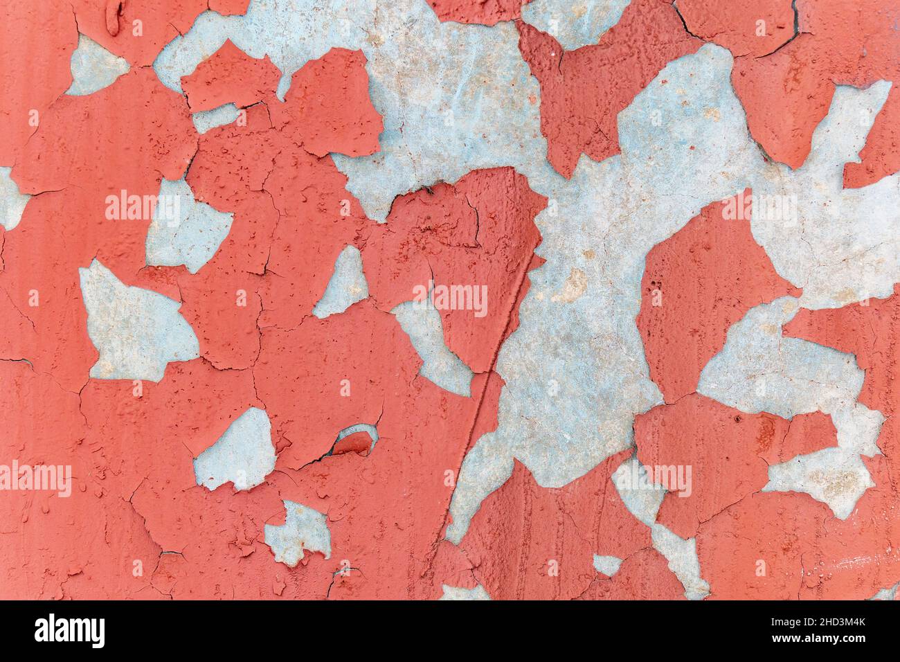 Old weathering cracks with peeling red paint smeared with cleaned wall ...