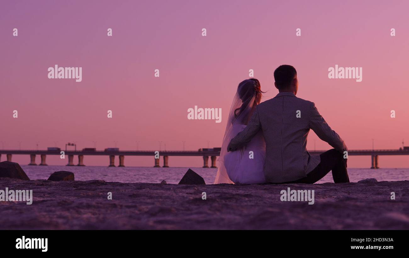 Scenic view of a married couple sitting on the beach on beautiful ...