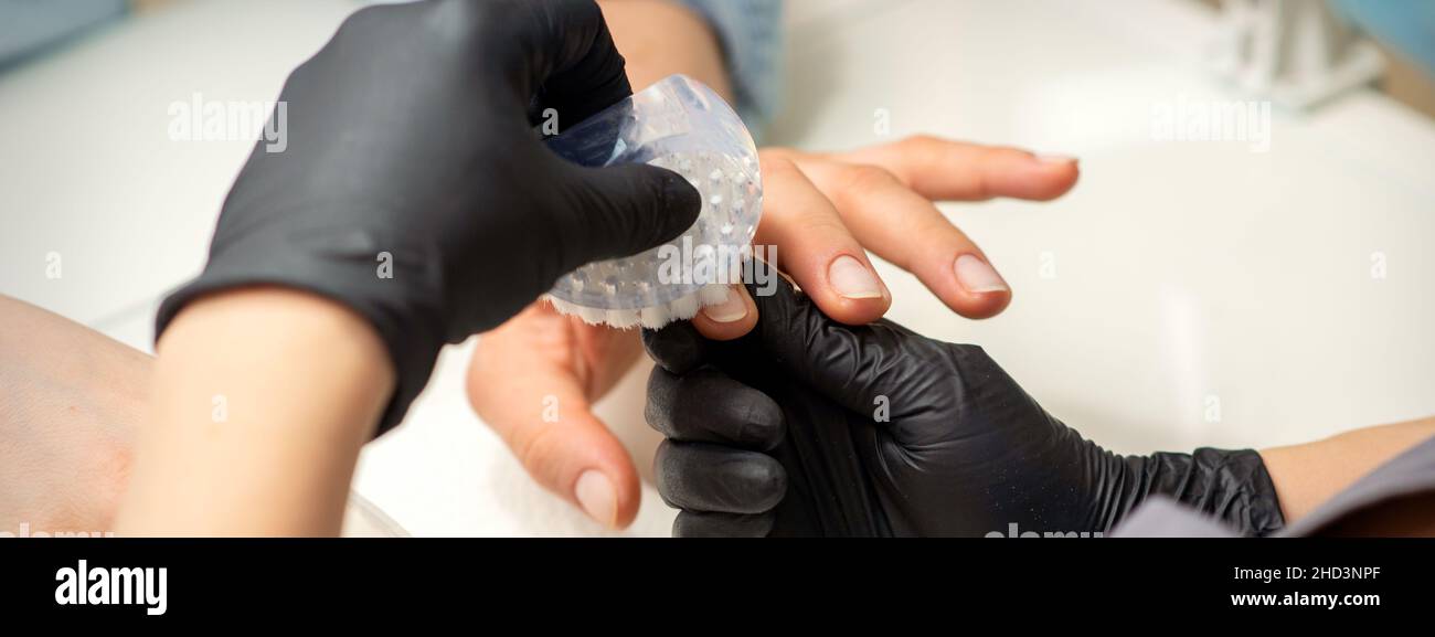 Hands of the manicure master removing dust from nails with a brush ...