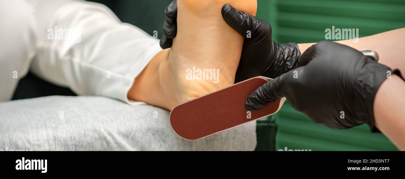 Peeling of Heels. Hands of pedicure master scrape dead from heel skin ...