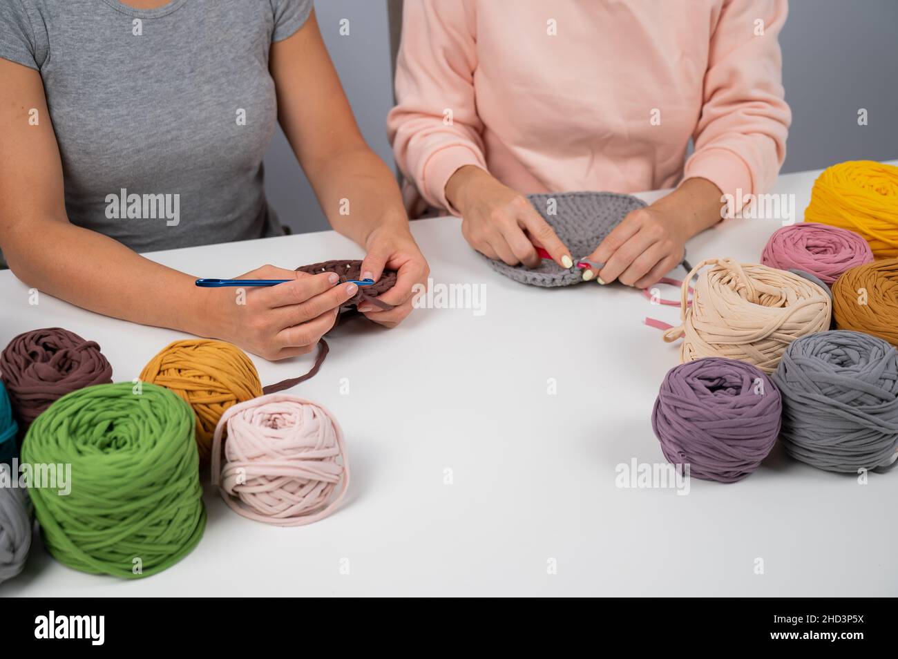 A woman teaches her friend needlework. Two women are crocheting a ...