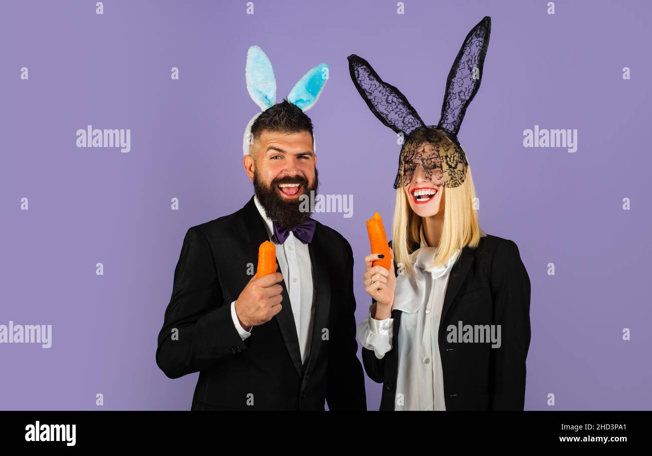 Easter bunny couple eat carrot. Funny couple wearing bunny ears. Bunny ...