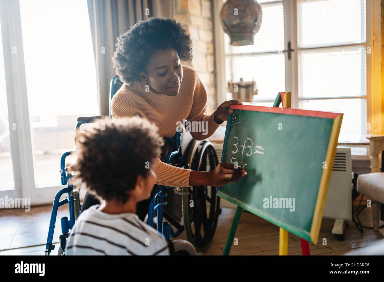Happy child doing math exercises with her mother ot teacher together ...