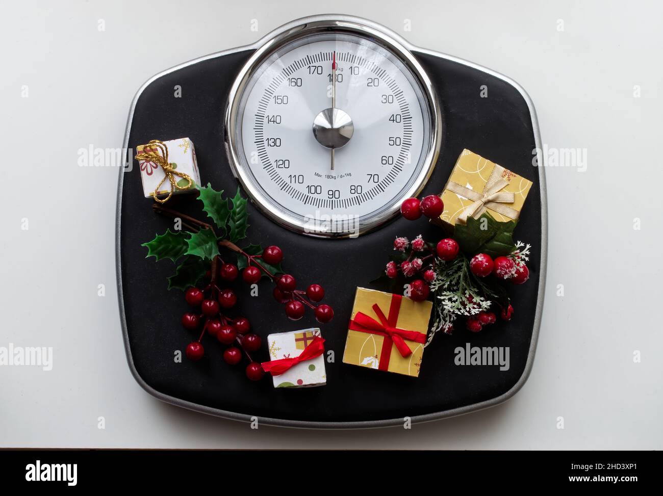 Analog scale surrounded by Christmas decorations and gifts. Overweight ...