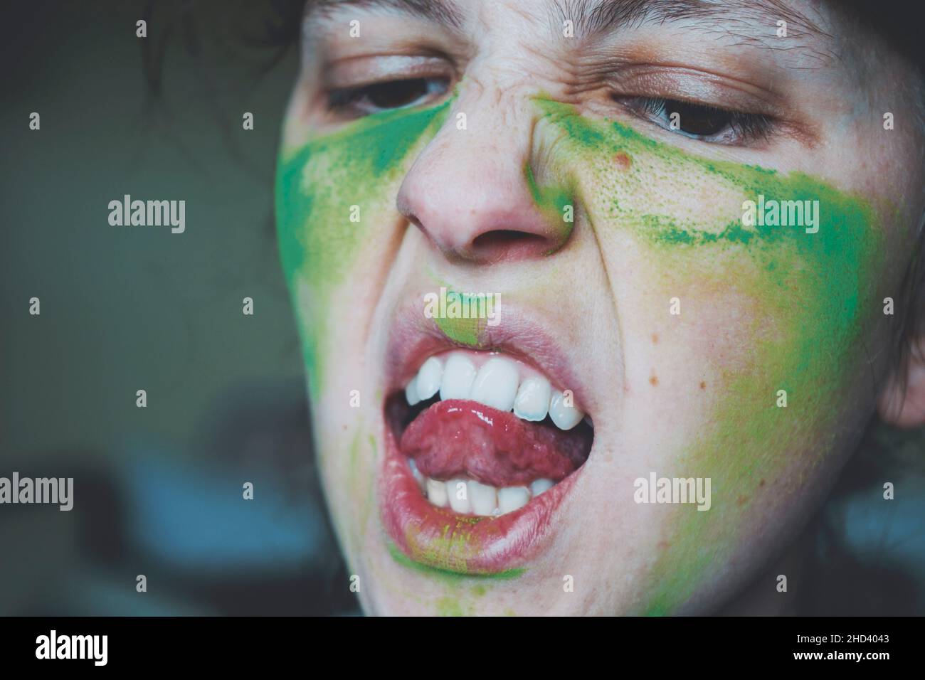 Angry young woman with her face painted with green dust Stock Photo - Alamy