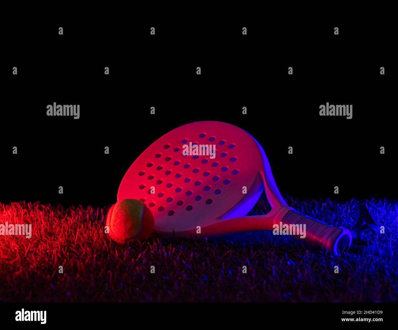 Beach and padel racket and ball on grass court with neon lighting. Blue ...