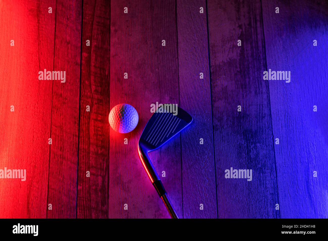 Golf stick and white ball on hardwood court floor with neon lighting ...