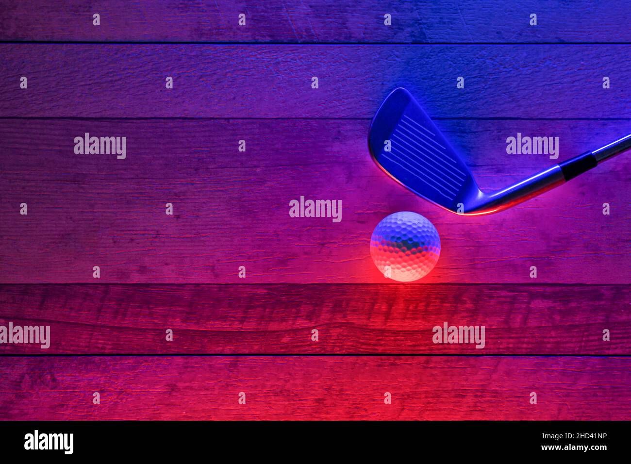 Golf stick and white ball on hardwood court floor with neon lighting ...