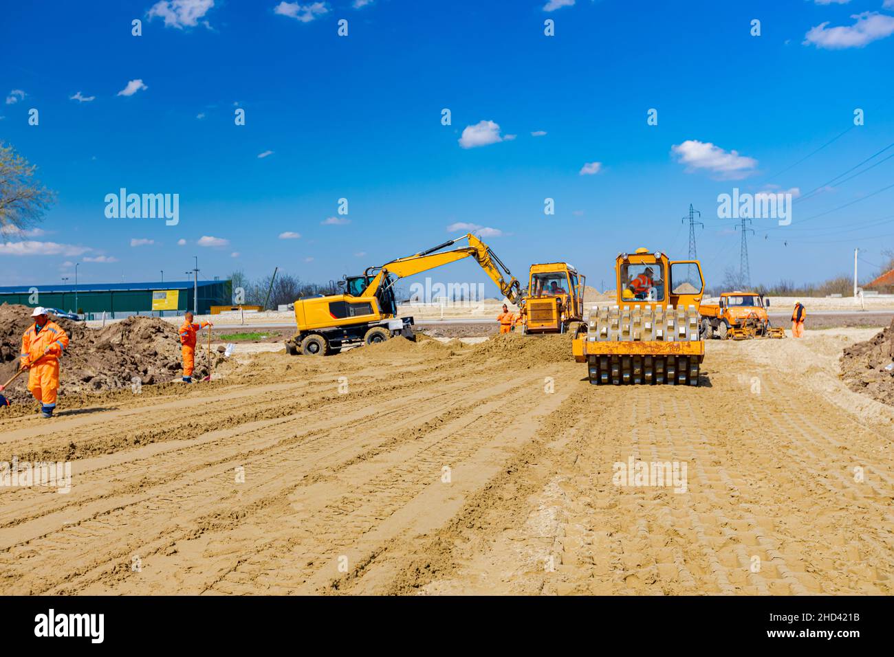 Road roller with spikes and bulldozer are compacting, leveling sand for ...