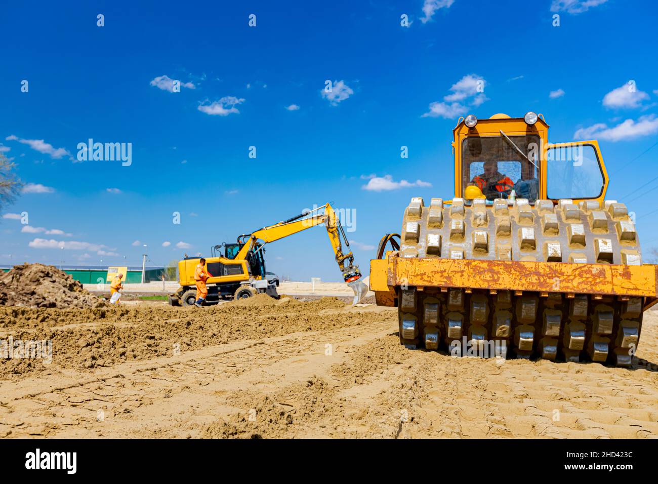 View over roller with spikes on bulldozer and excavators are leveling ...