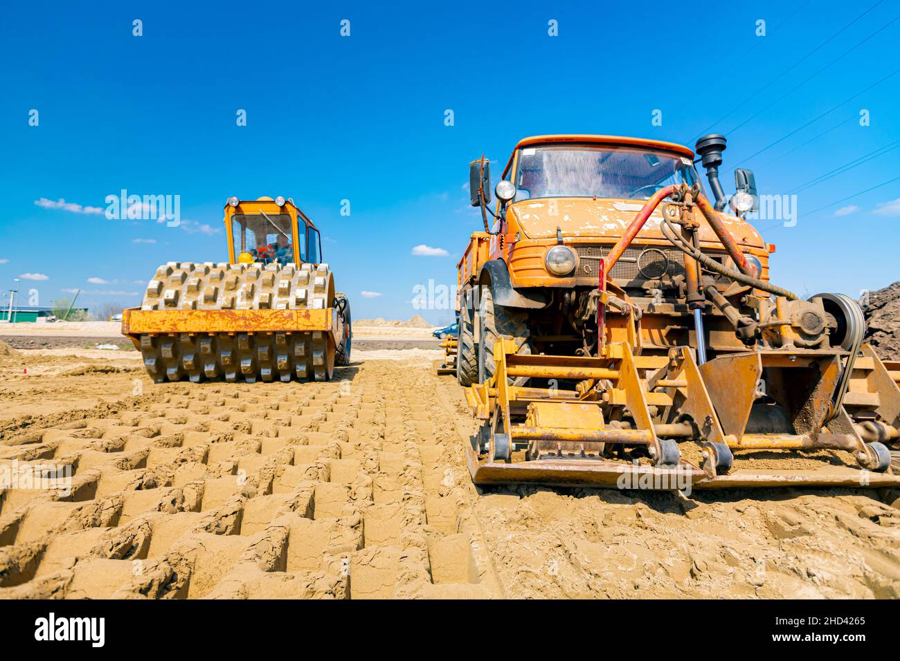 Road roller with spikes and truck with mounted plate vibration ...