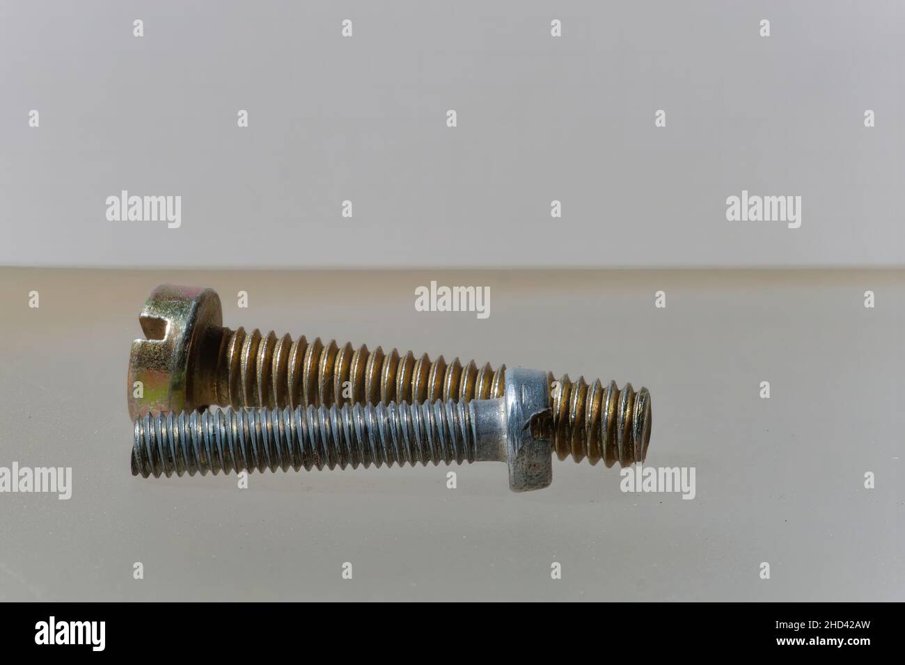 Close-up picture of a rusty gold and silver screw on a white background ...