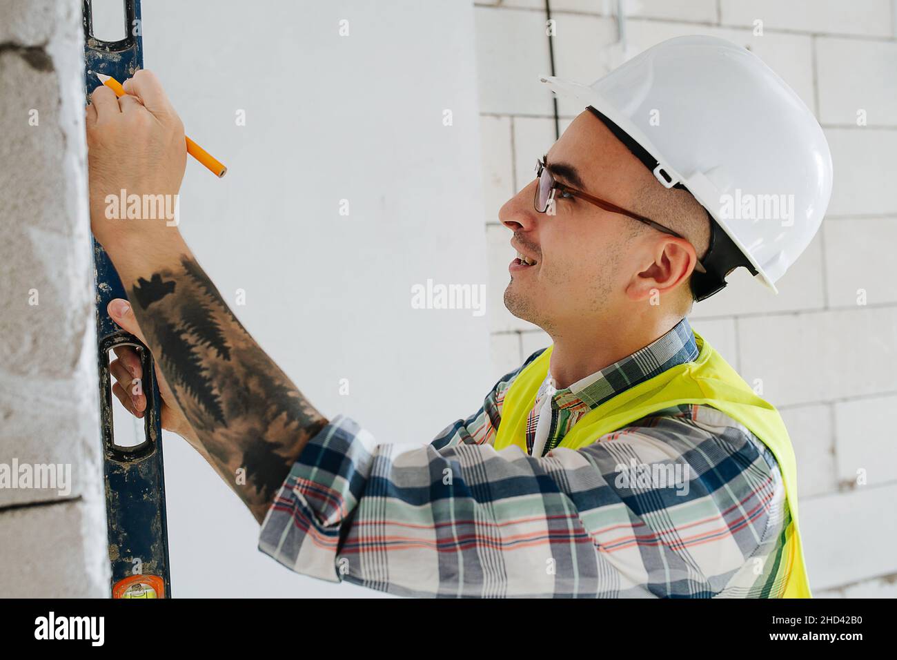 Scrupulous construction engineer in a white helmet making marks on a ...