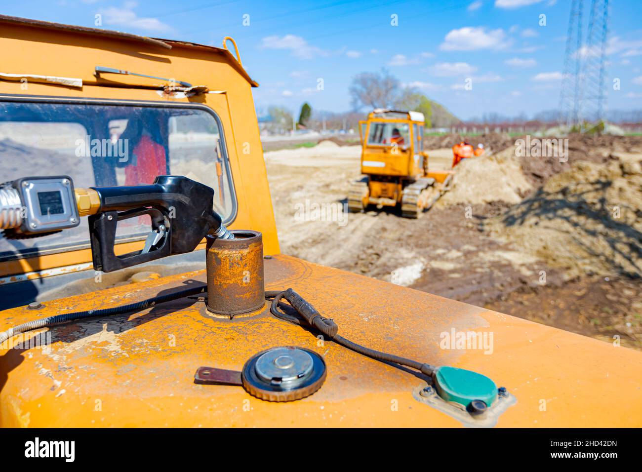 Fuel pump gun inserted in the reservoir of construction machine, pour ...