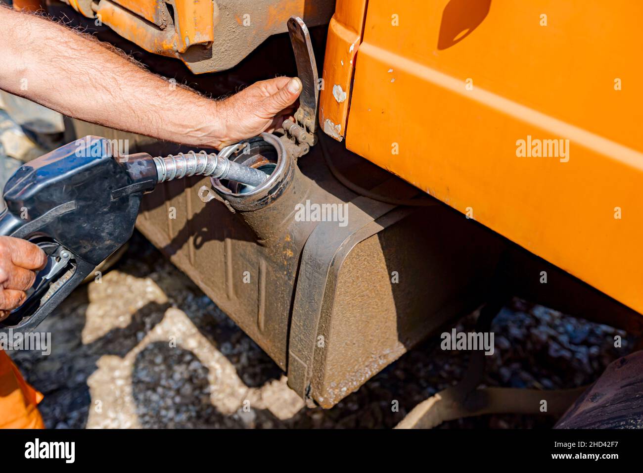 Worker holding fuel pump gun inserted in the reservoir of construction ...
