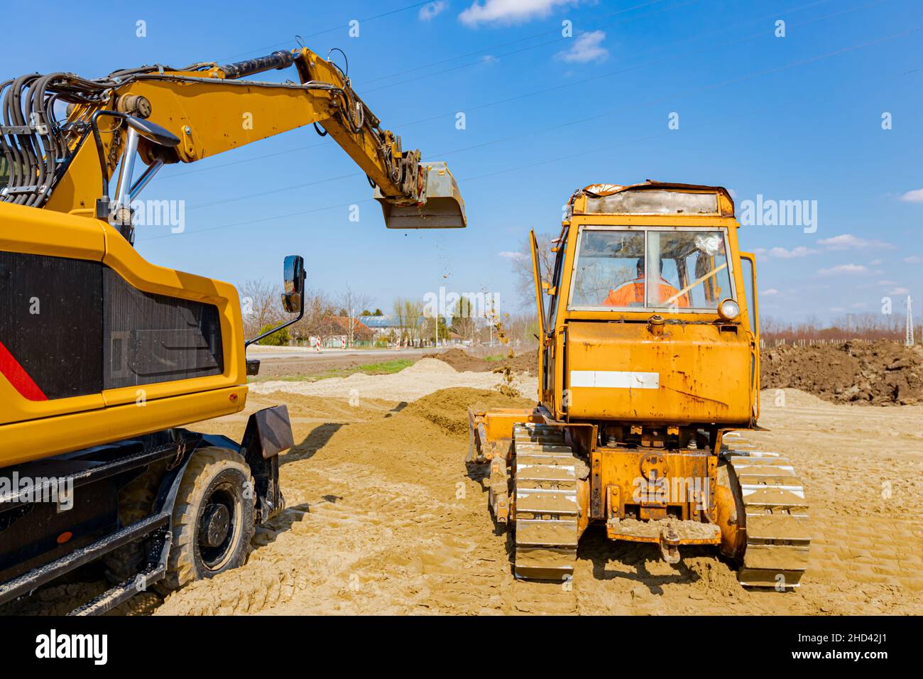 View from behind on bulldozer and excavator that are leveling sand for ...