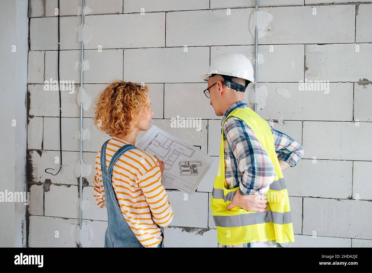 Behind view of an engineering team going over a blueprint, discussing ...