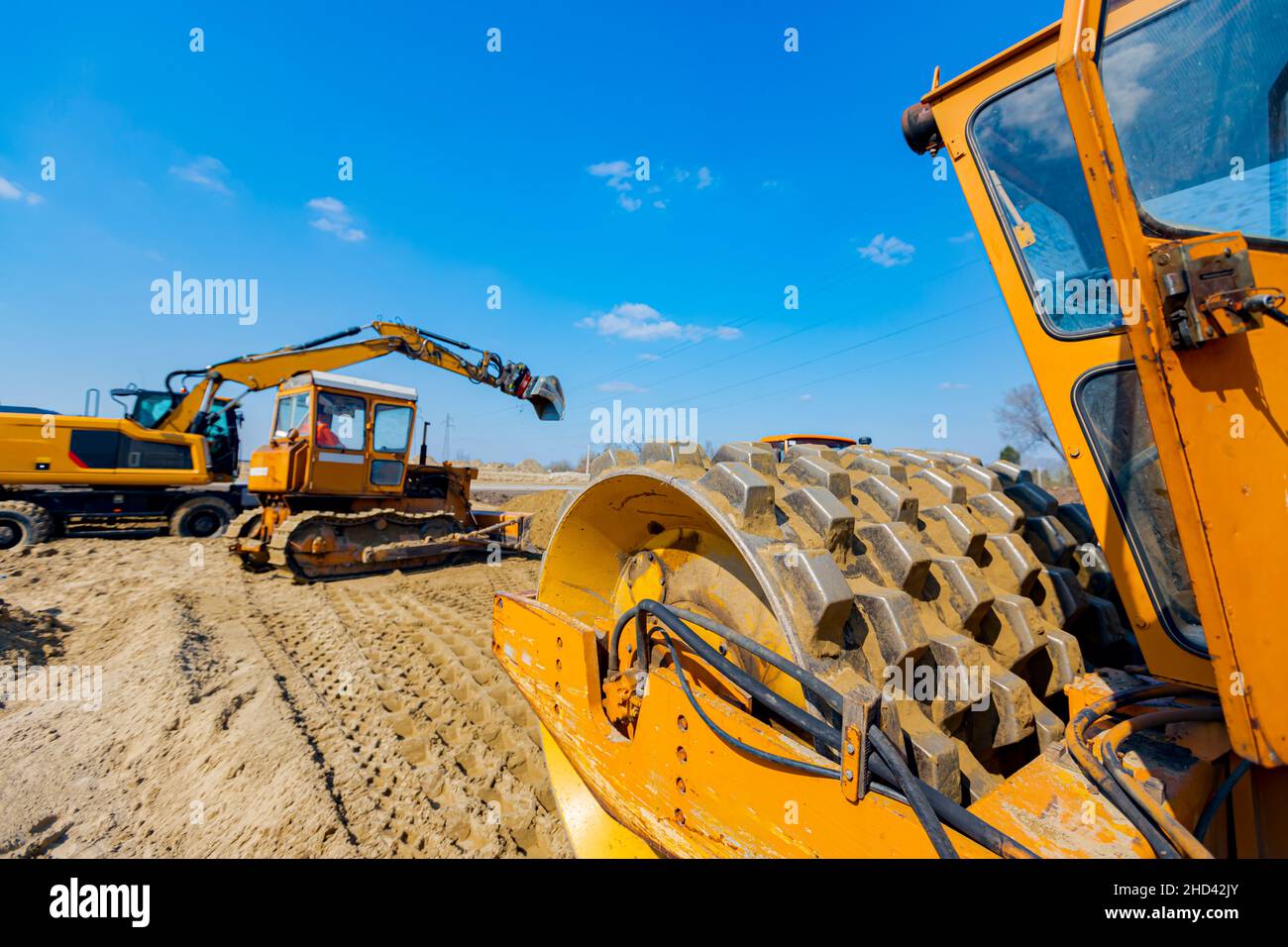 View over roller with spikes on bulldozer and excavators are leveling ...