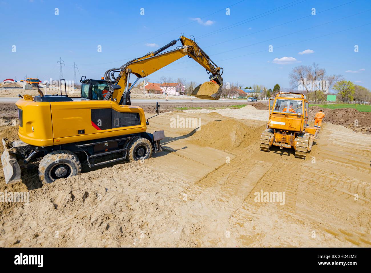 View from behind on bulldozer and excavator that are leveling sand for ...
