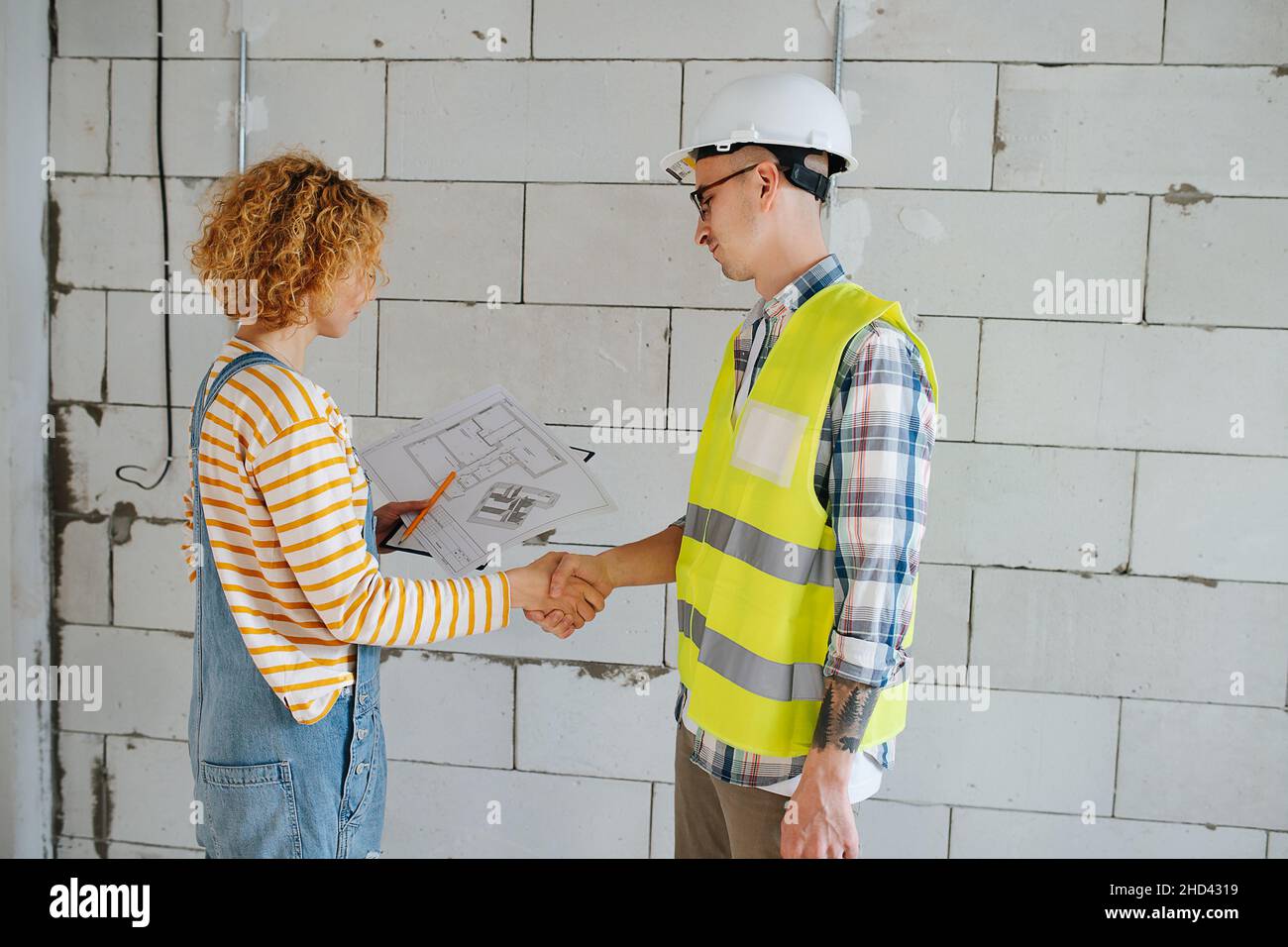 Busy engineer team looking at a blueprint, reaching agreement, shaking ...