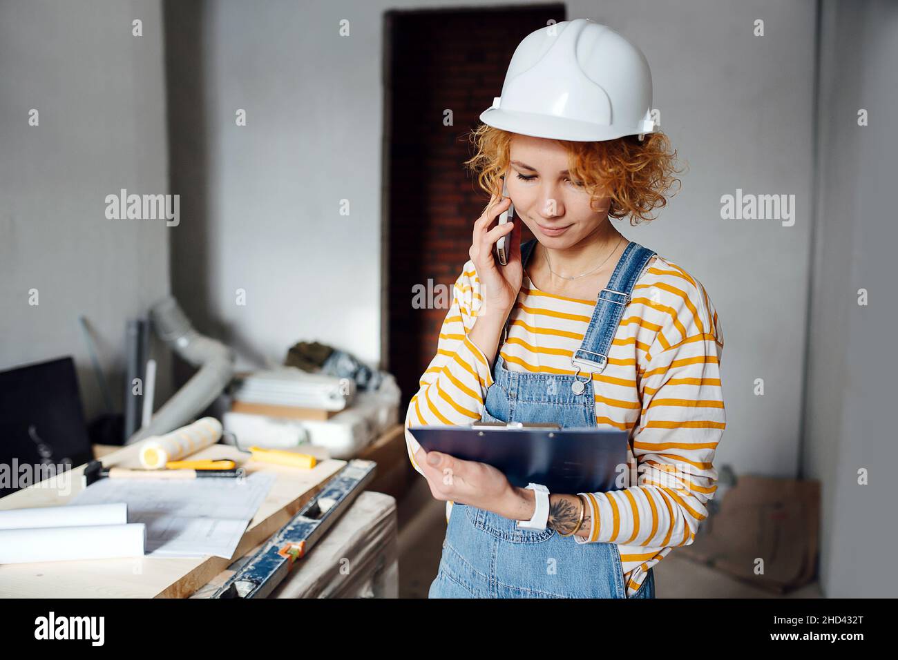 Subtly smiling female construction engineer in a white helmet looking ...