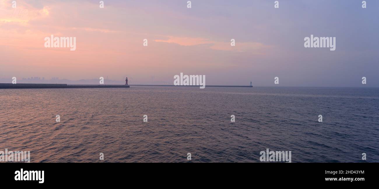 Scenic view of a lighthouse in the port of Dalian on a sunset sky ...