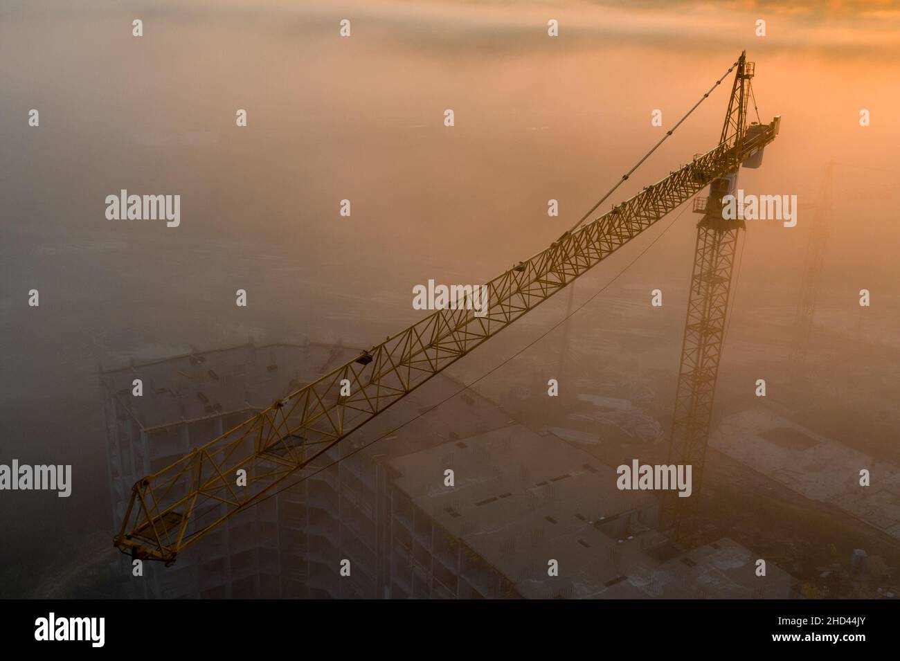 Construction site at dawn. Tower cranes over fog on the background of ...