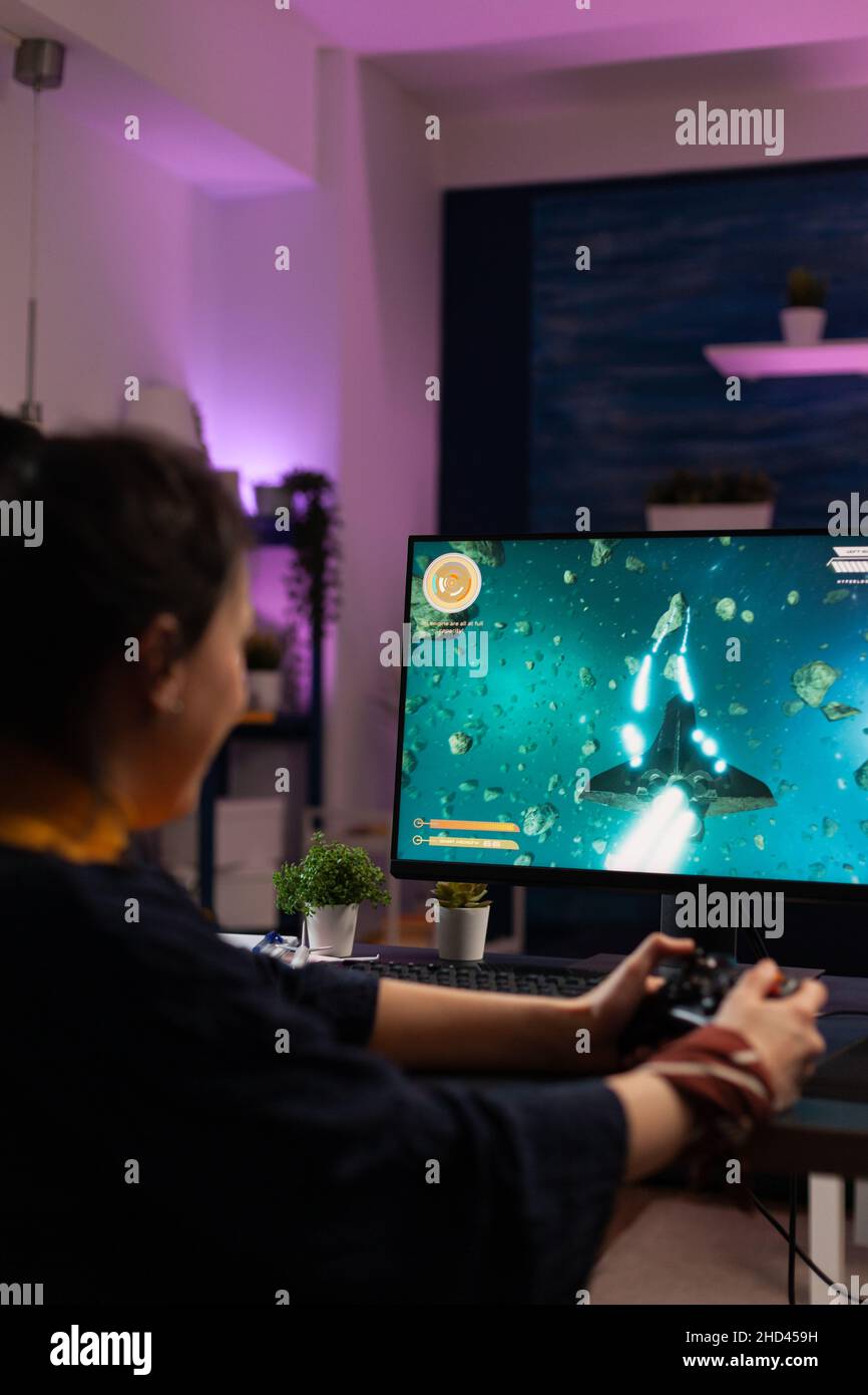 Gamer playing video games with joystick on monitor. Cheerful woman ...