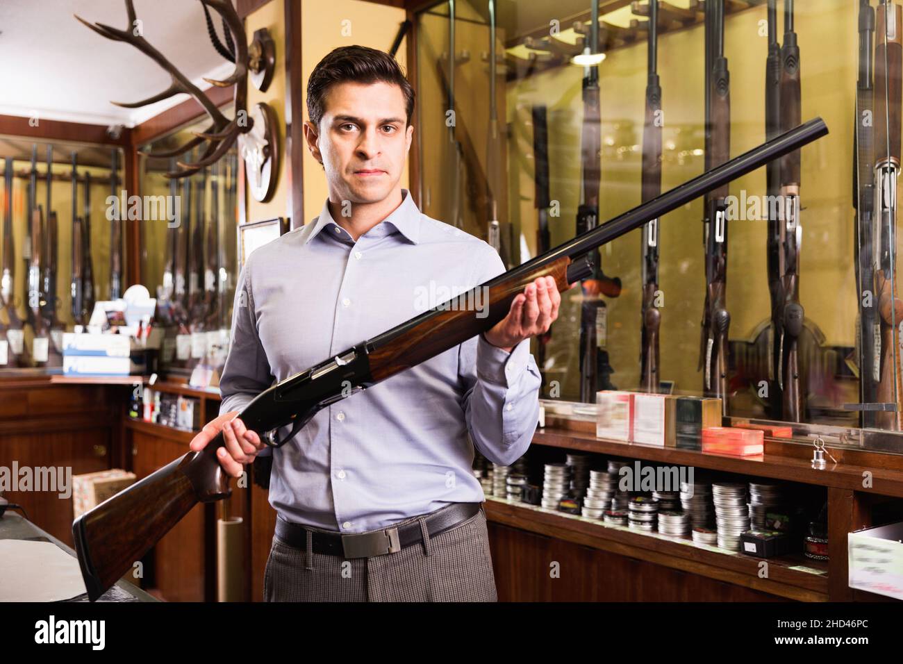Handsome adult male in hunting shop with rifle in hands Stock Photo - Alamy