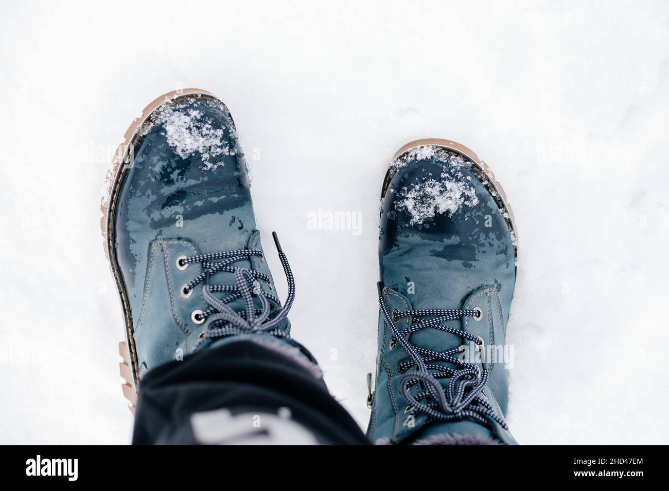 Closeup photo of winter blue warm boots with laces out in snow making ...