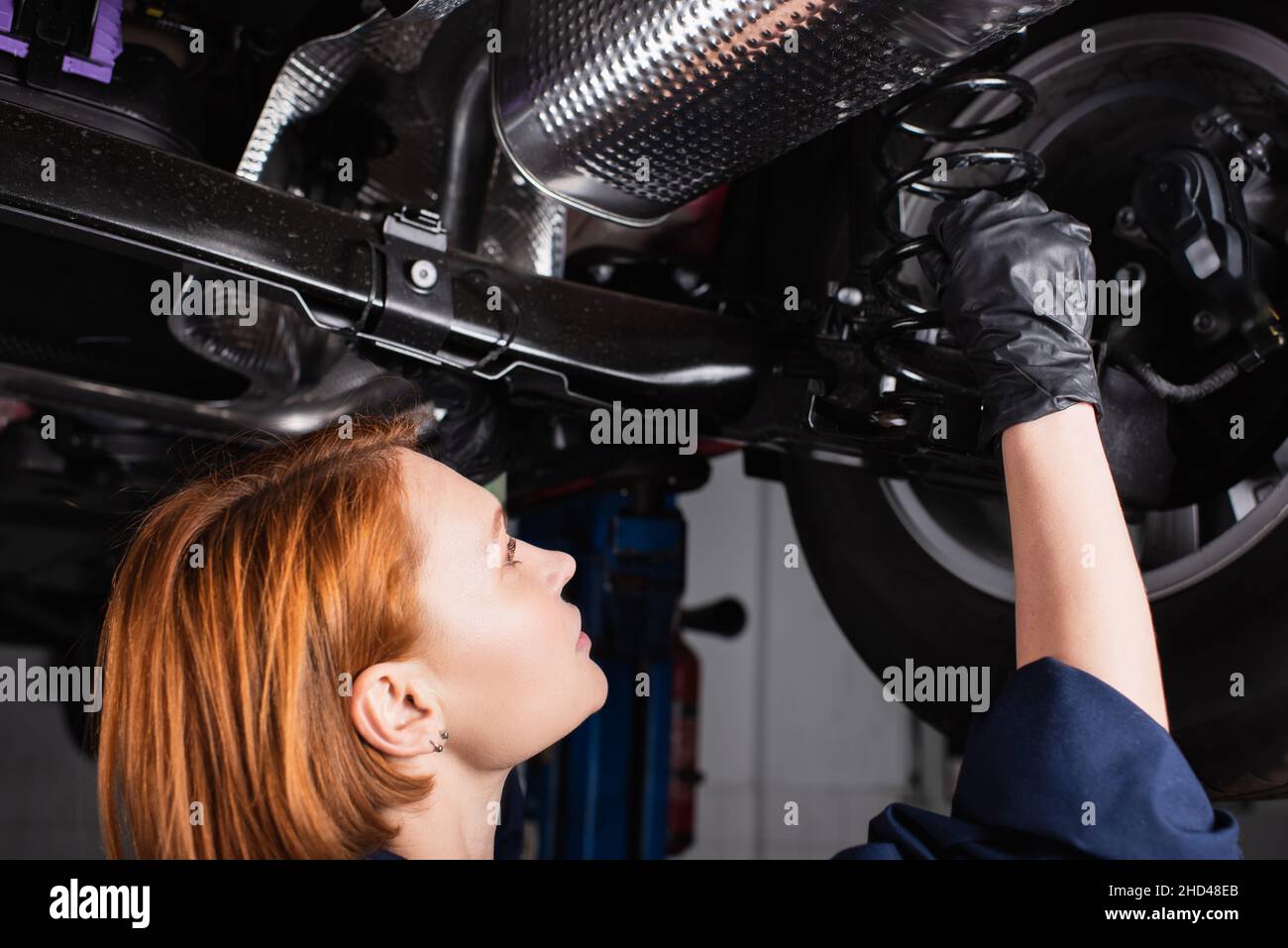 Side view of redhead mechanic working with car in service Stock Photo ...