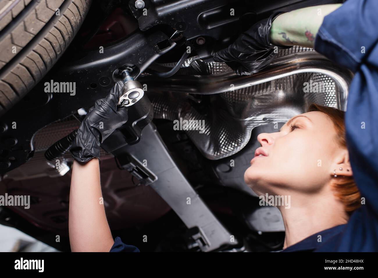 Low angle view of mechanic working with wrench and car in garage Stock ...