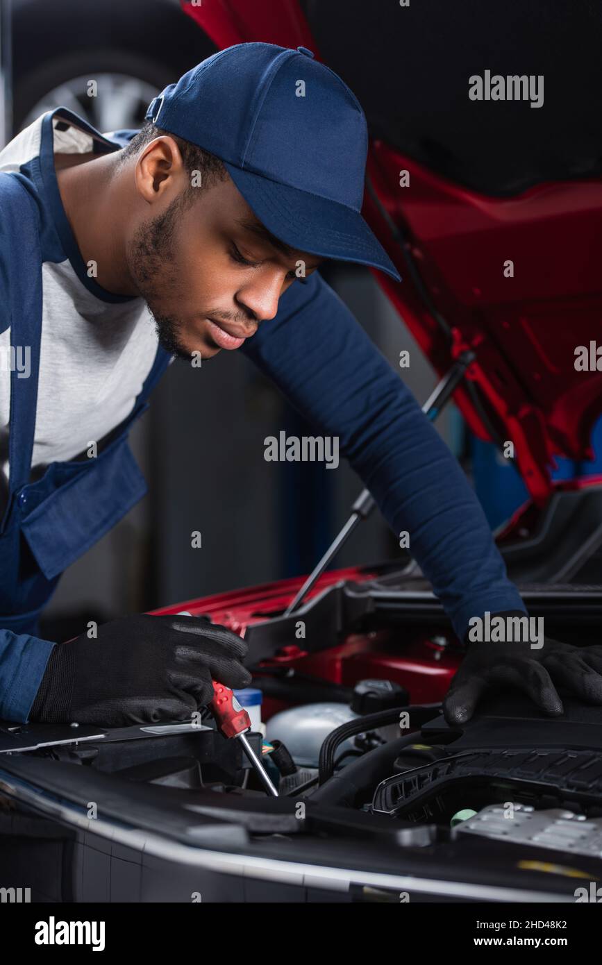 african american foreman with screwdriver making diagnostics of car ...