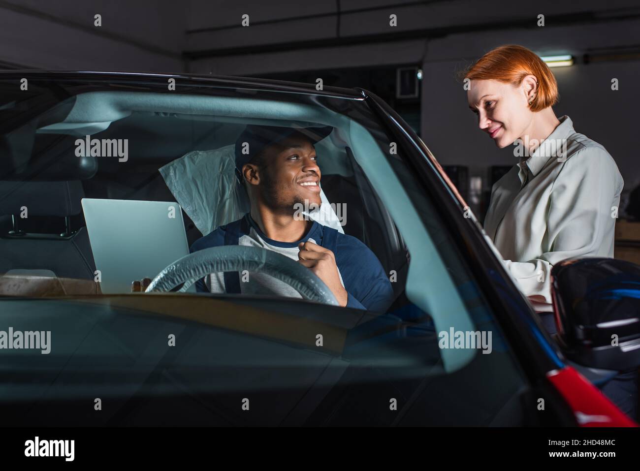 smiling african american foreman with laptop making diagnostics of car ...
