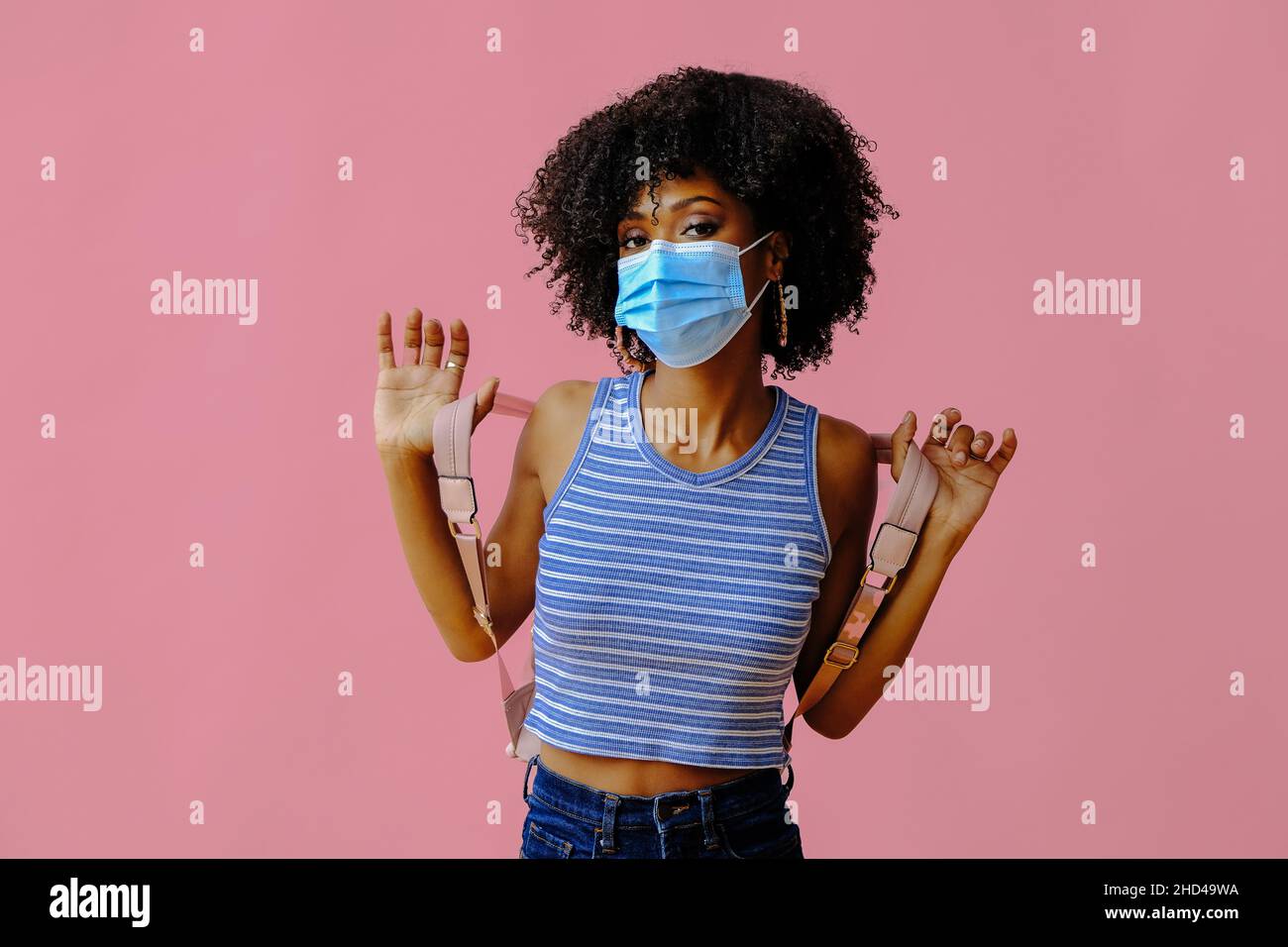 young female student with backpack wearing protective mask and posing ...