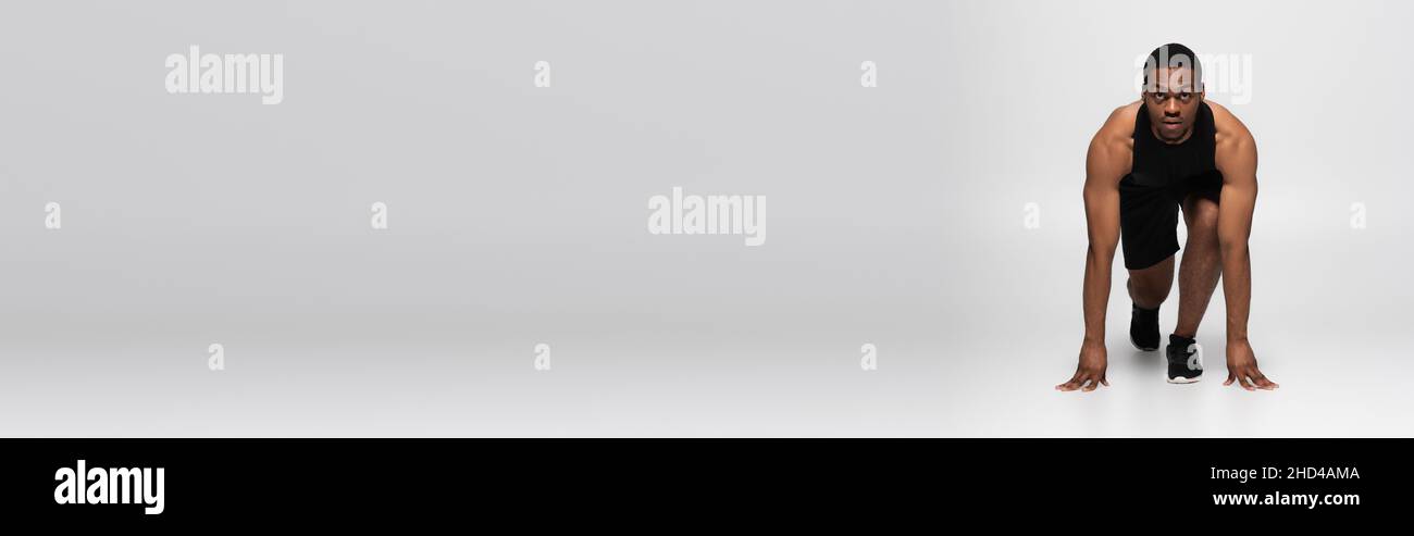 full length of african american sportsman in starting pose before ...