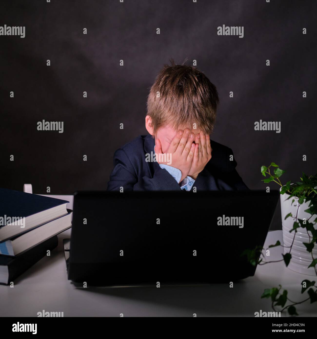 A sad boy in a school suit is crying at the computer, copy space on a ...