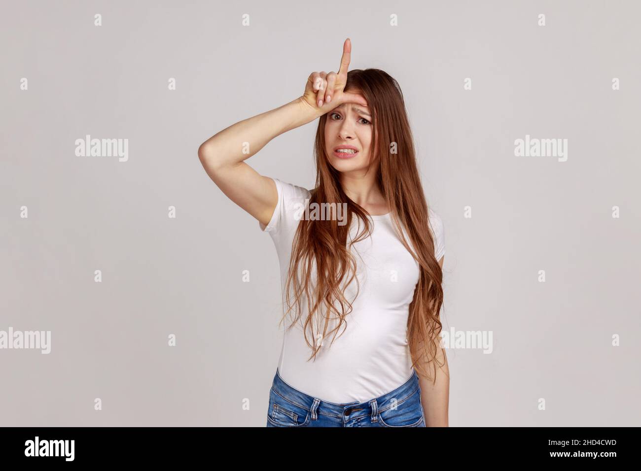 Portrait of displeased young woman standing with hand on forehead ...