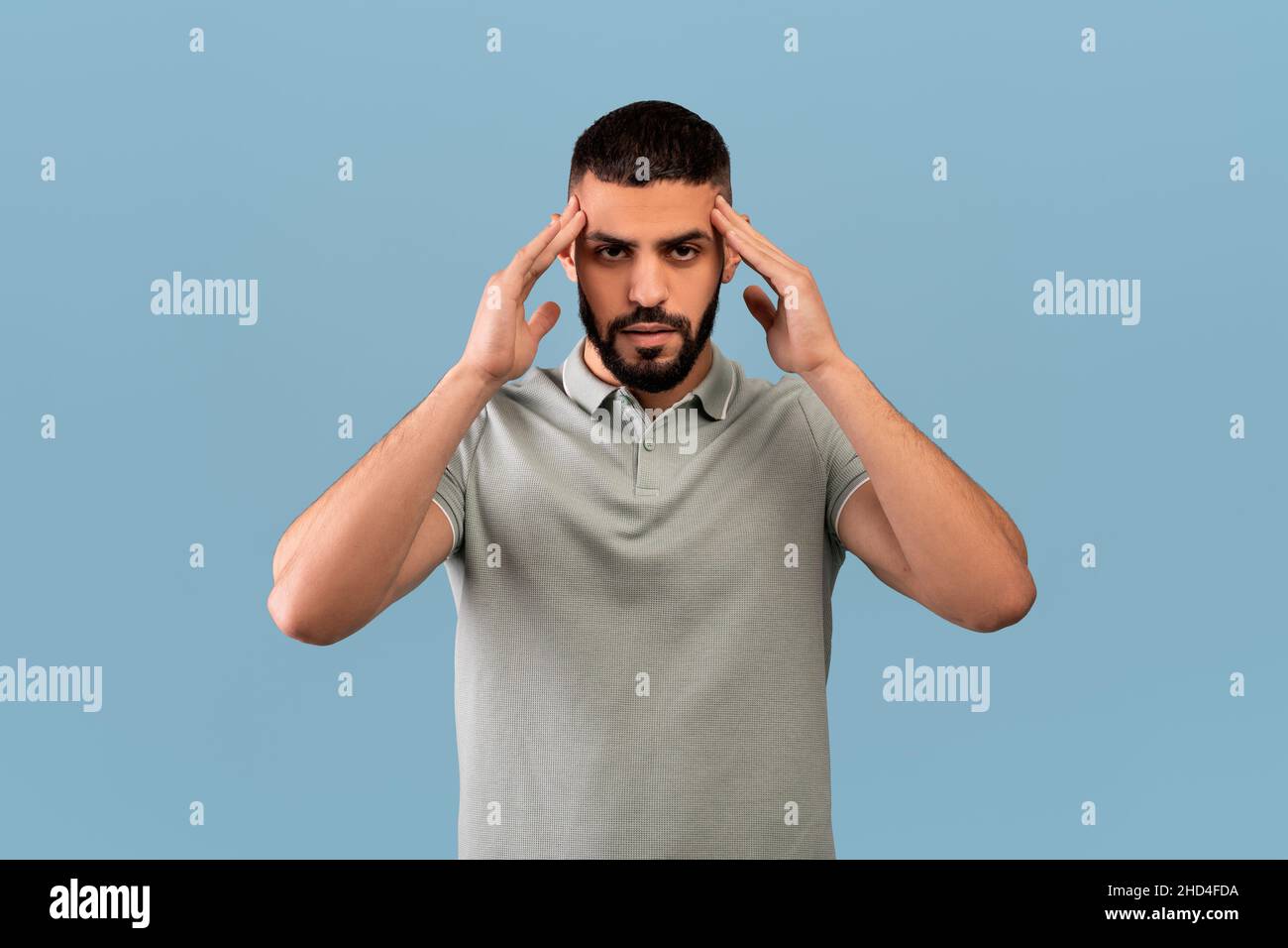 Middle eastern man suffering from headache, massaging temples to get ...