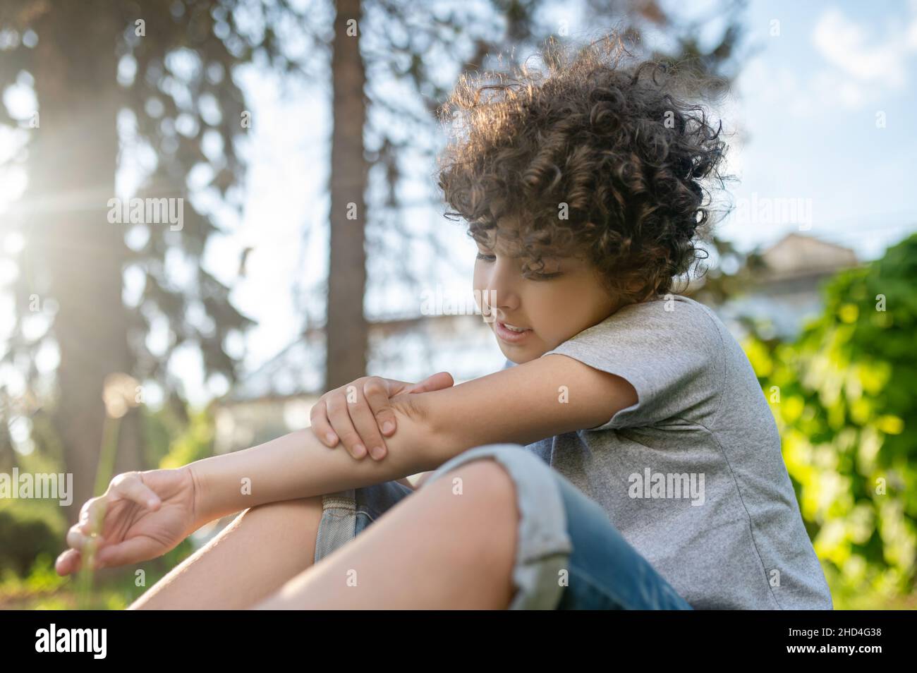 Concentrated kid examining his damaged elbow joint Stock Photo - Alamy