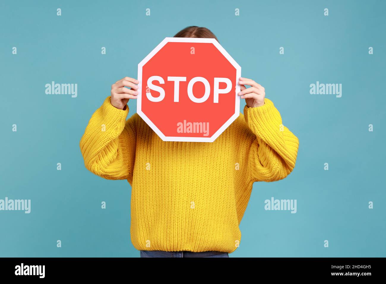 Portrait of unknown little kid covers face with Stop symbol, anonymous ...