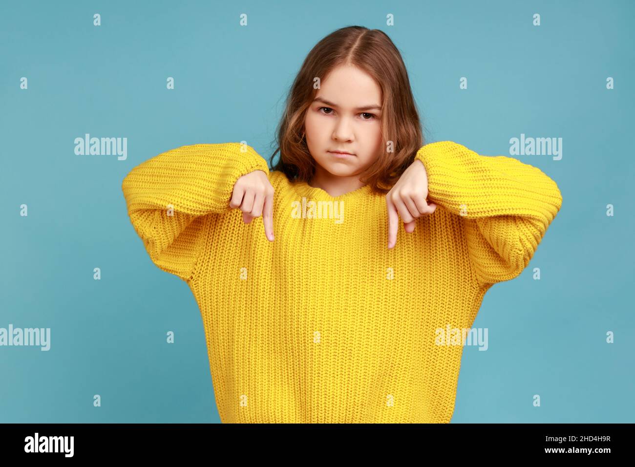 Portrait of little girl pointing down, gesturing below with strict ...