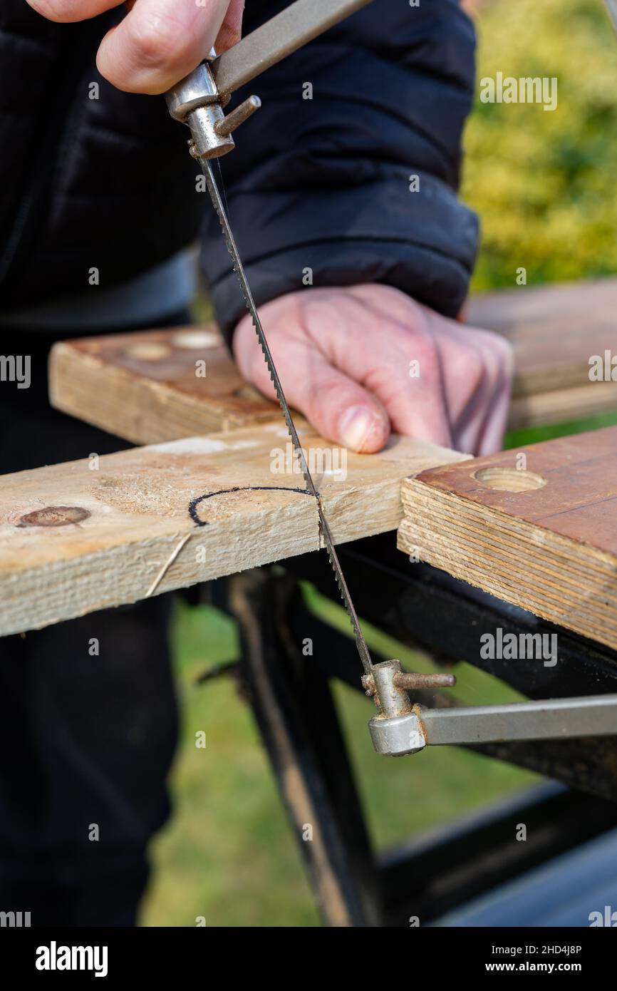 Close up of a person using a coping saw to cut a semi circle out of a ...