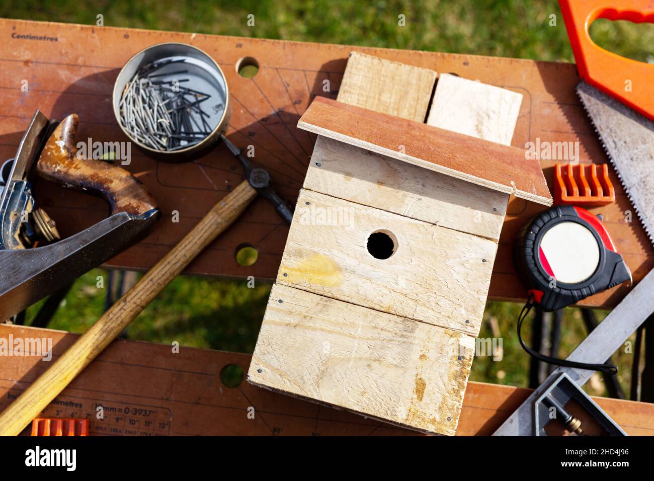 A handmade bird box laying on a workbench with the tools used ...