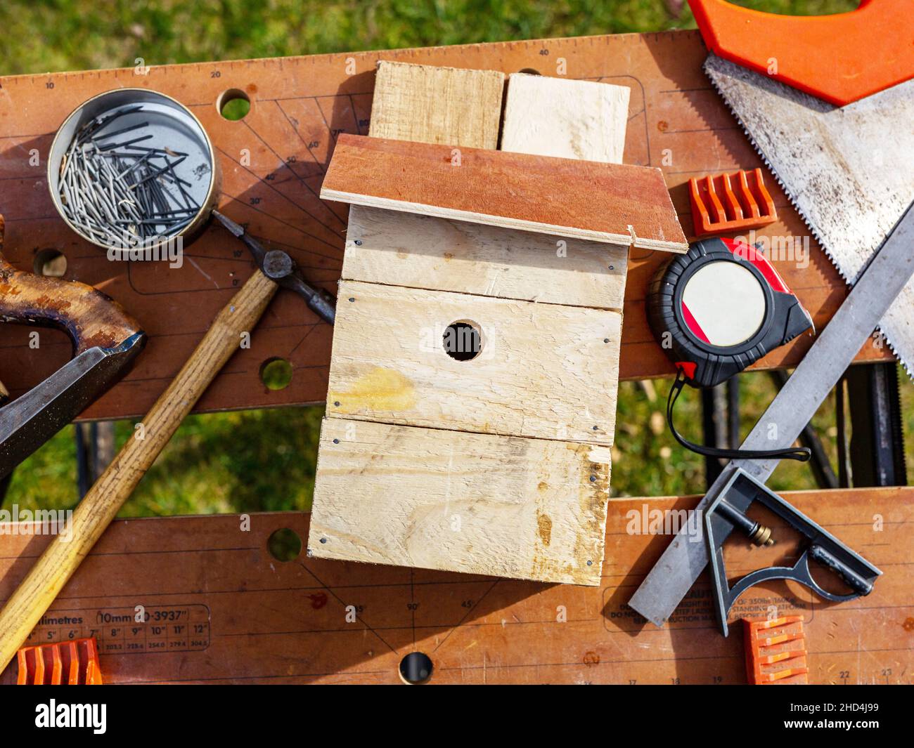 A handmade bird box laying on a workbench with the tools used ...