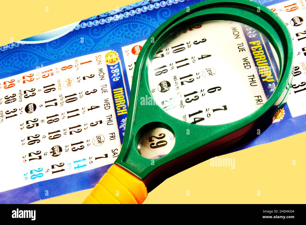Closeups shot of a magnifying glass on a calendar on a yellow ...